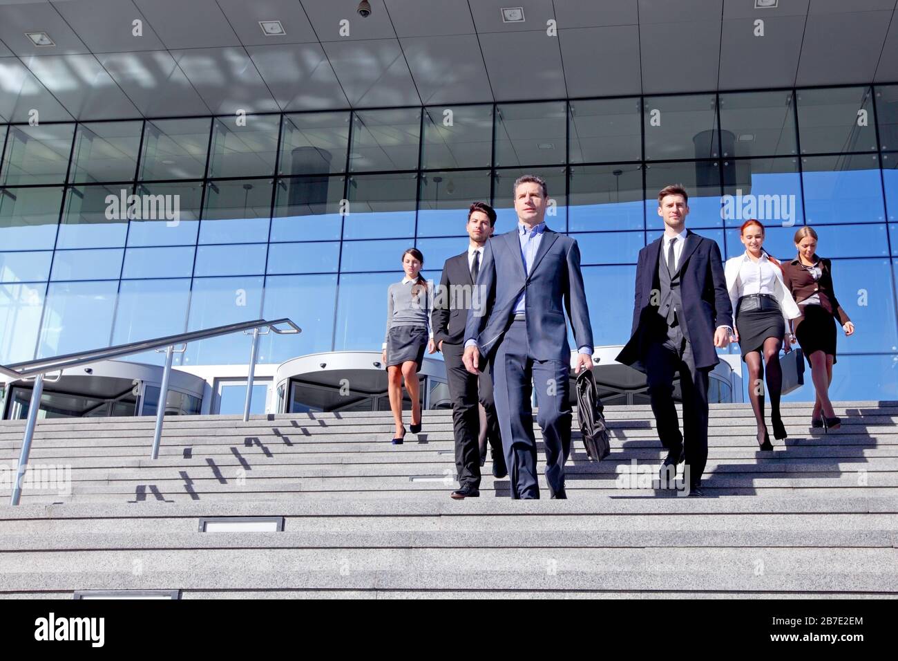 Group of business people and their leader walking down stairs outside ...