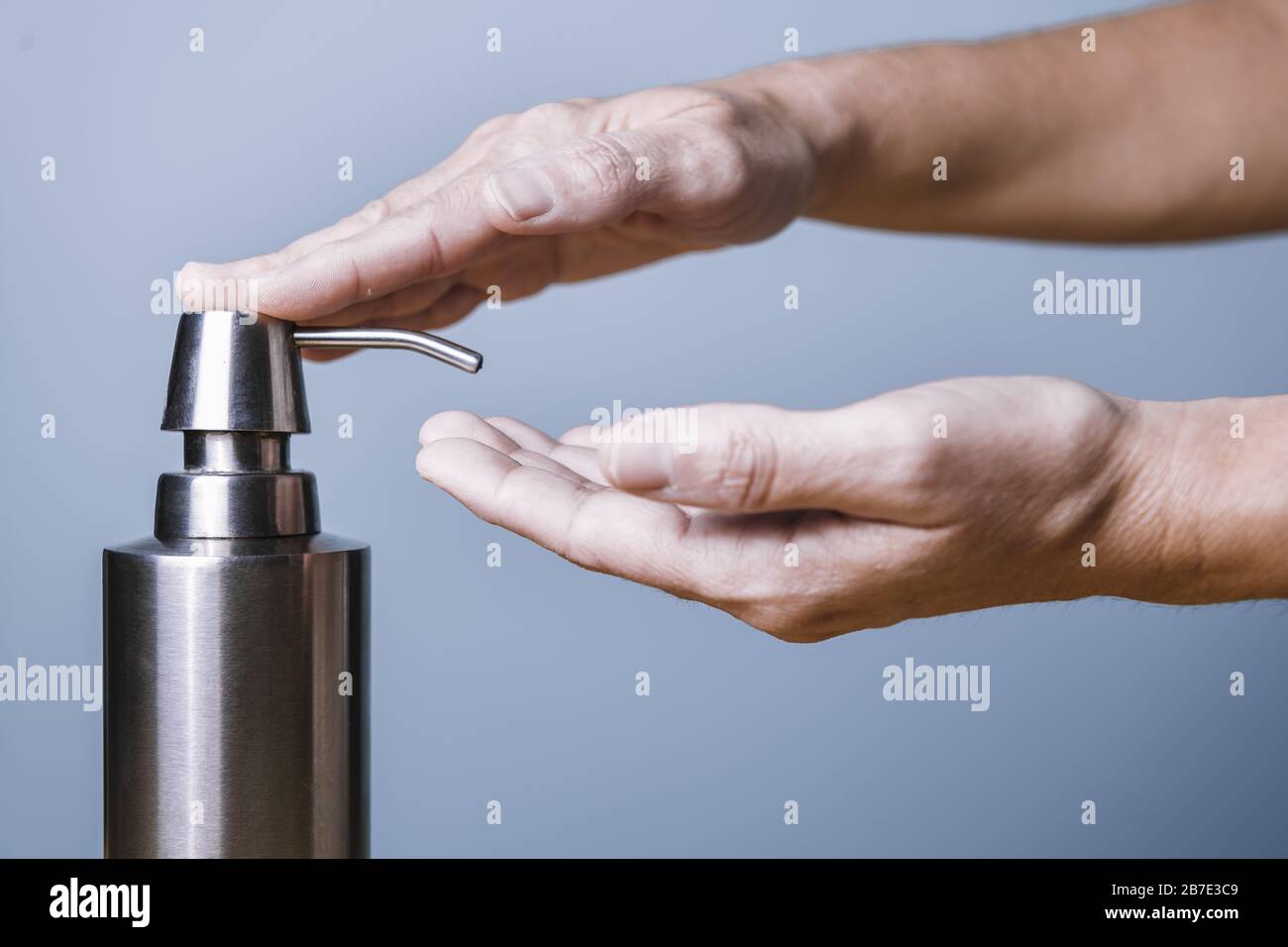 hands putting on soap with a dispenser over blue background, hygiene ...
