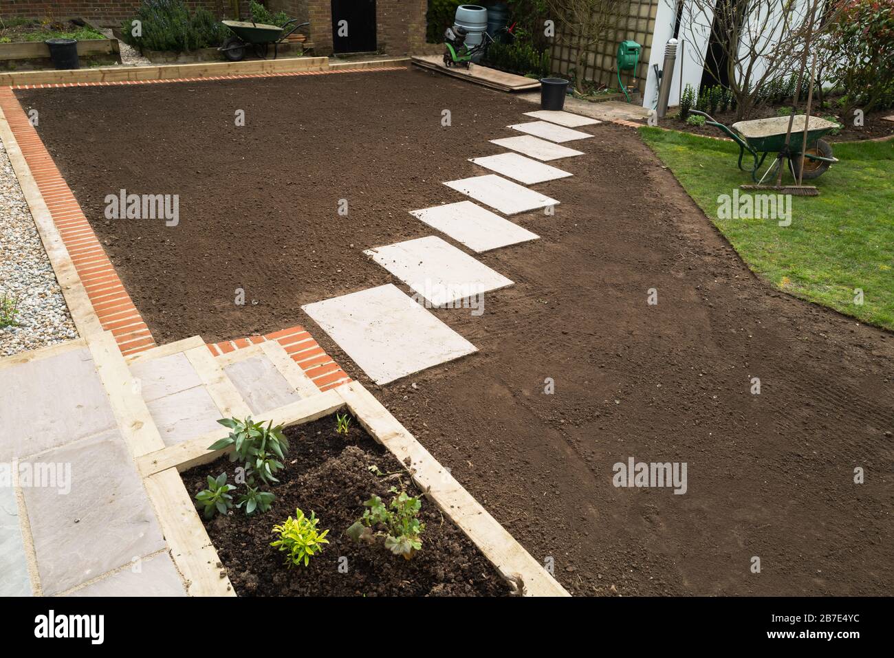 New stepping stone slabs along a landscaped garden with soil prepared ...