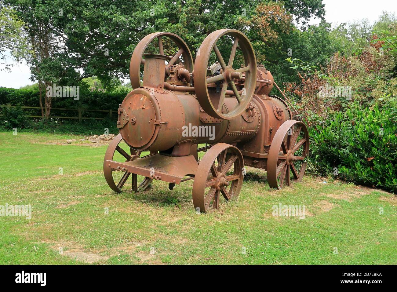 A landscape scene with green trees and grass with an old traction ...