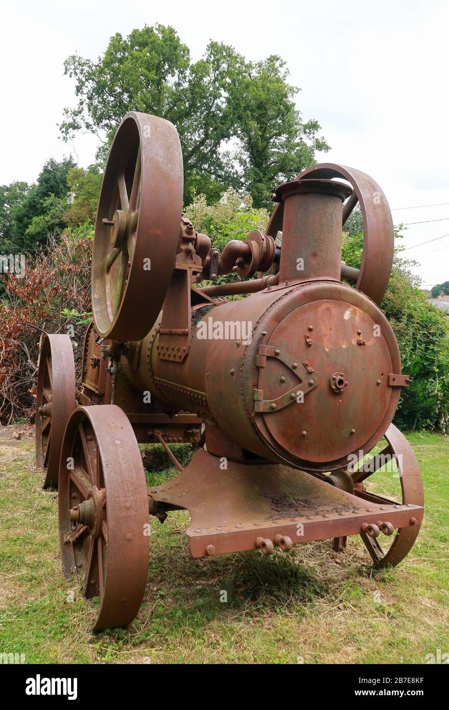 A landscape scene with green trees and grass with an old traction ...