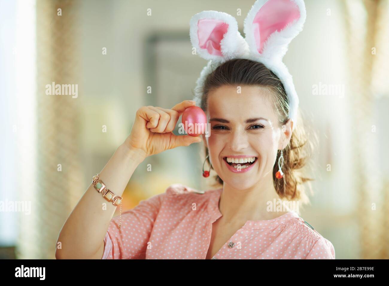 smiling middle age housewife in a pink blouse and easter bunny ears in ...