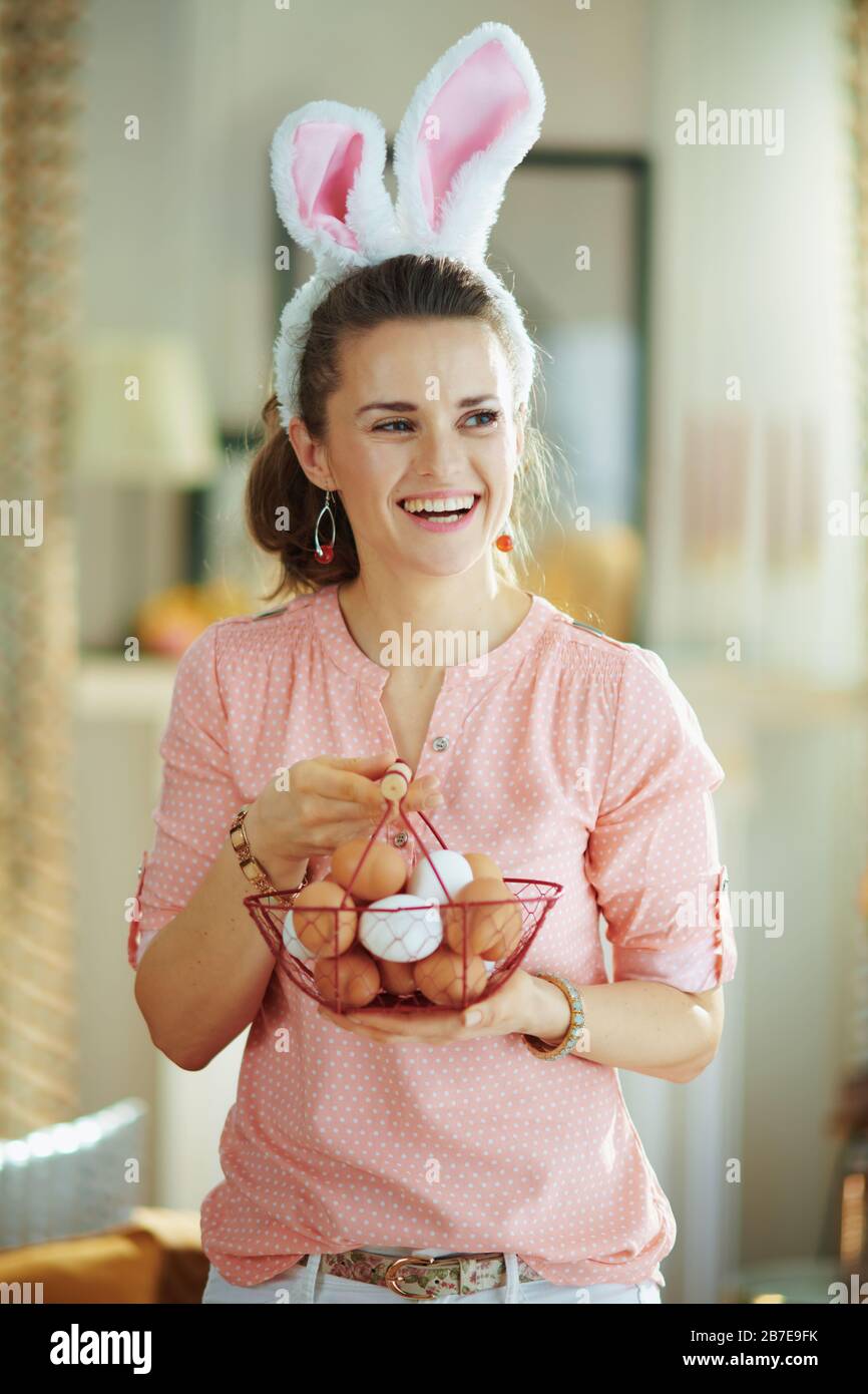happy elegant middle age woman in a pink blouse and easter bunny ears ...