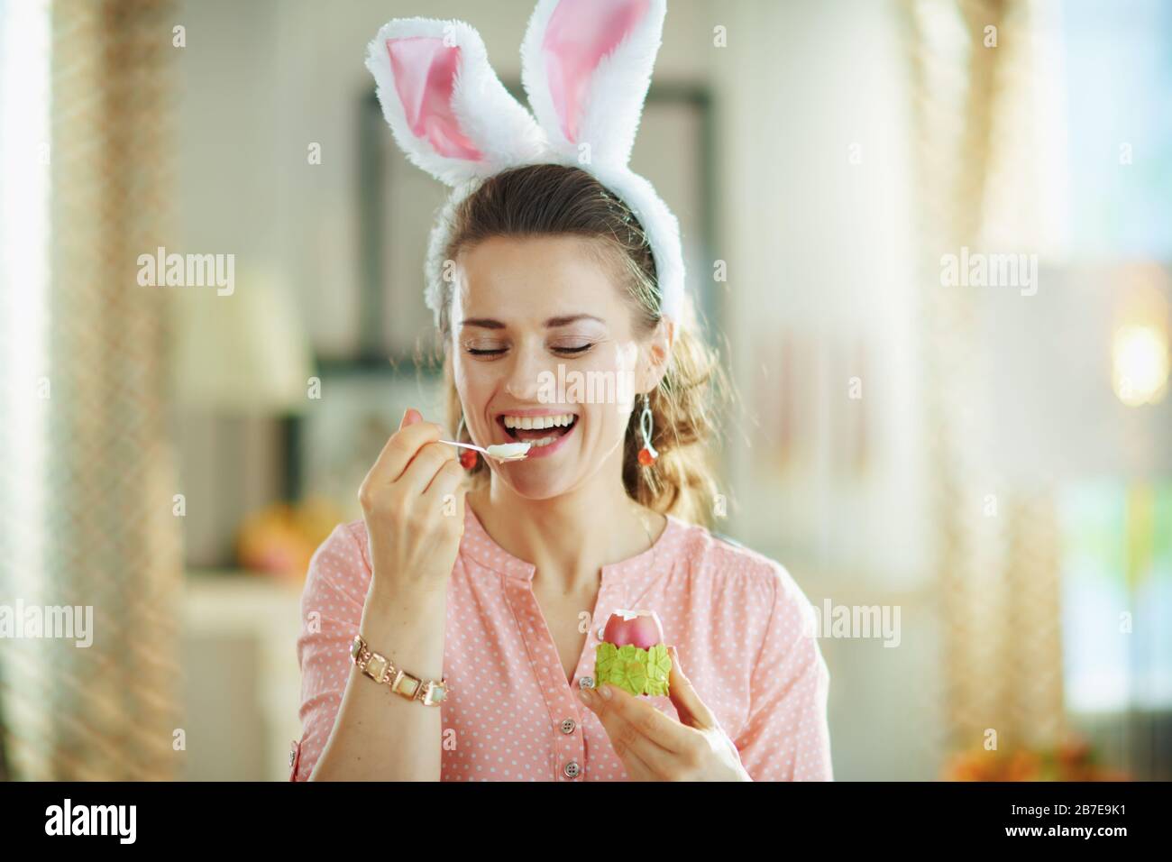 happy modern middle age woman in a pink blouse and easter bunny ears ...