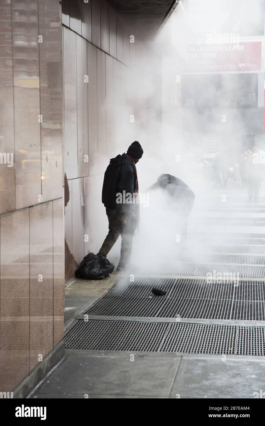 Homeless men warm themselves in the steam coming up through grates on ...