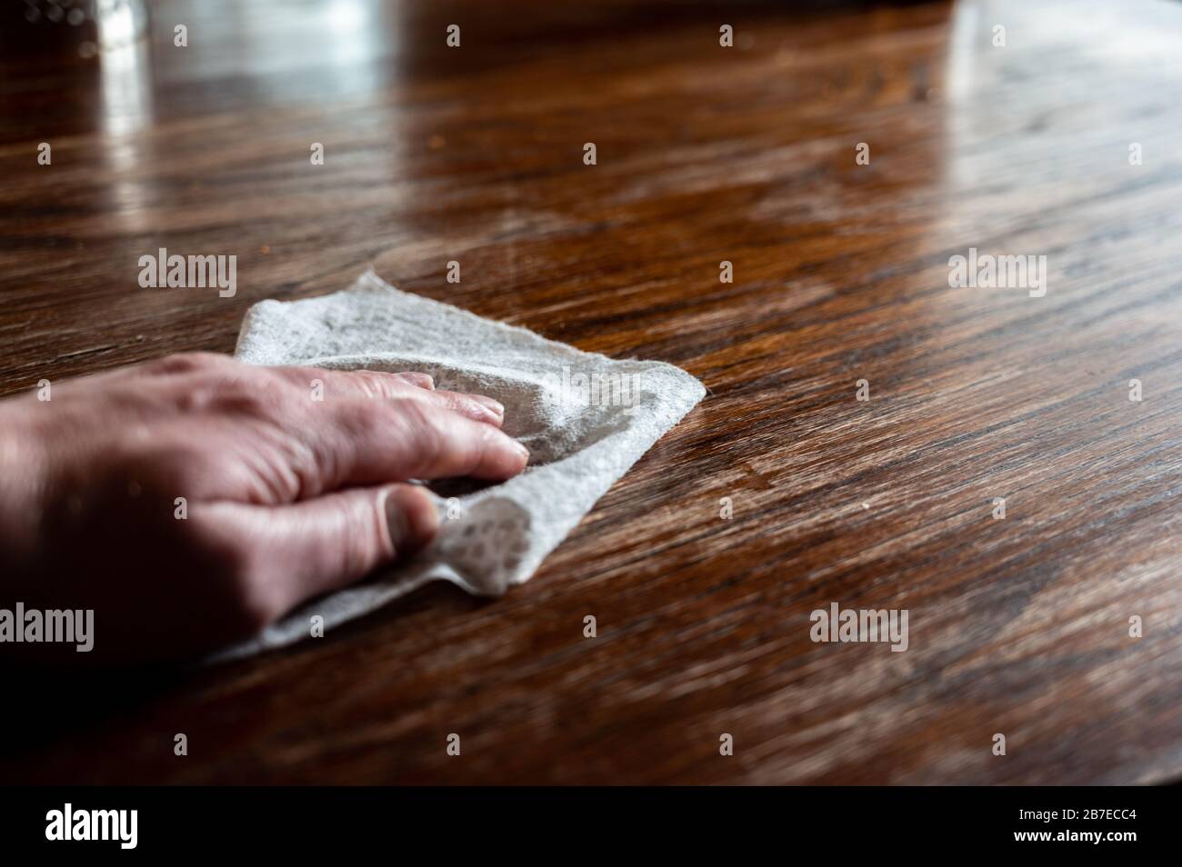 Hand holding sanitizing wipe on wooden table top Stock Photo - Alamy