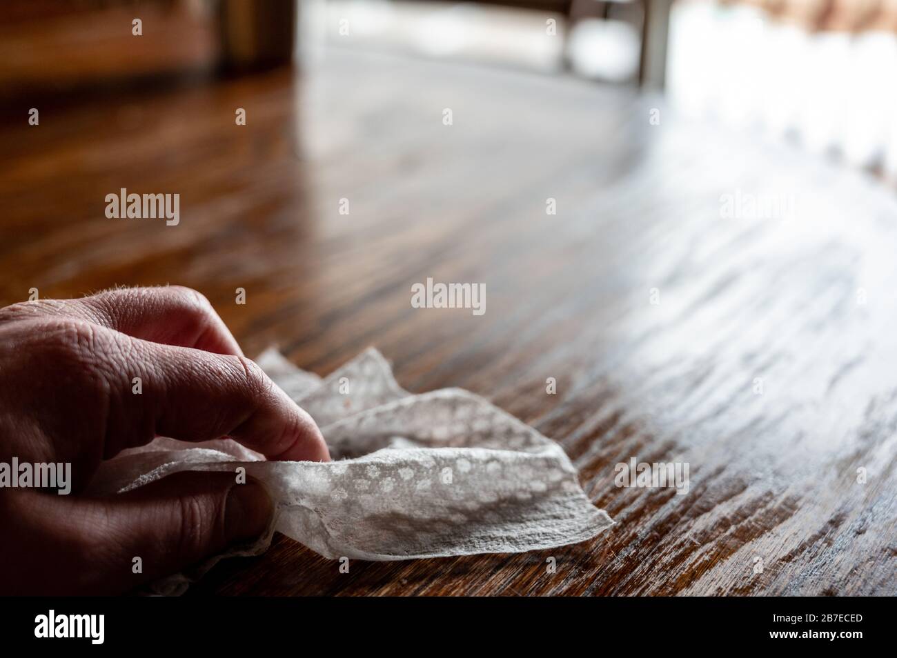 Hand holding sanitizing wipe on wooden table top Stock Photo - Alamy