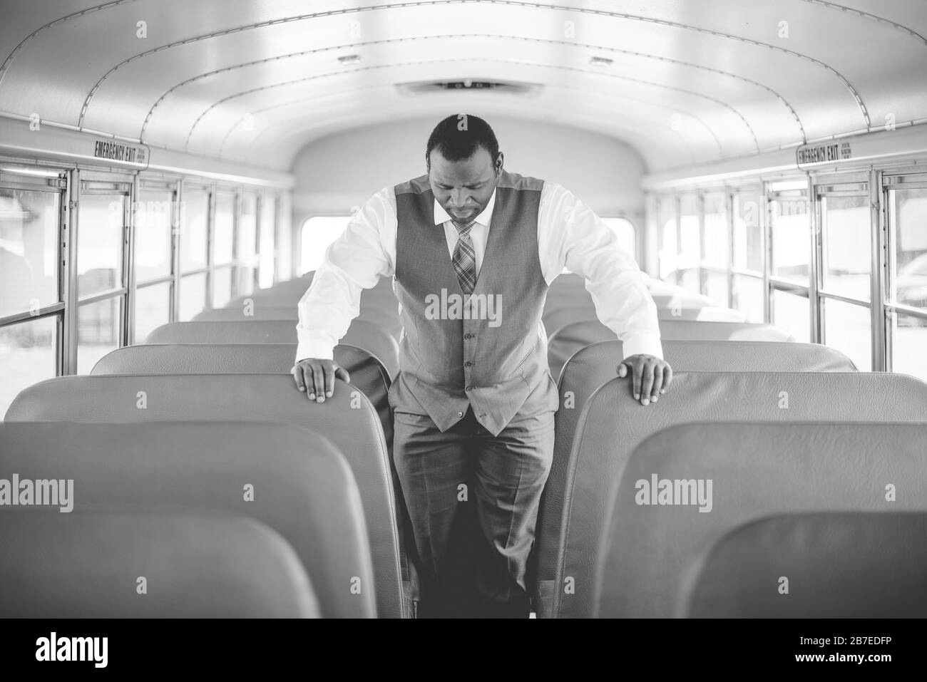 A lonely African-American male in a formal outfit praying on the bus ...