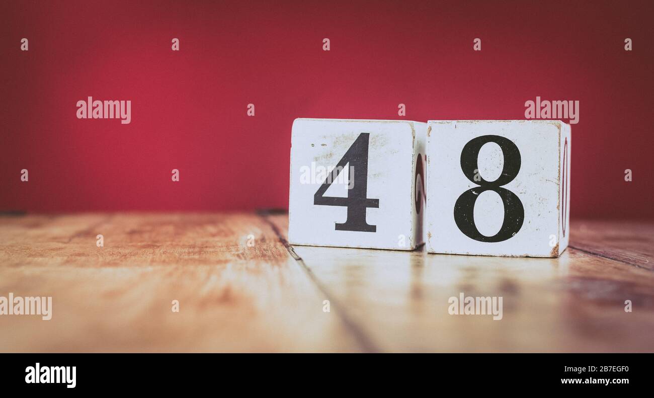 Number 48 on a vintage wooden table and dark maroon background - retro ...