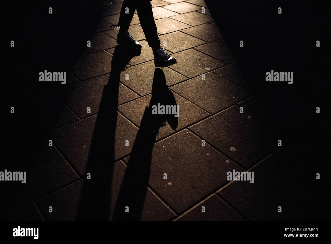 Shadow of a man wearing sneakers walking on paved street Stock Photo ...