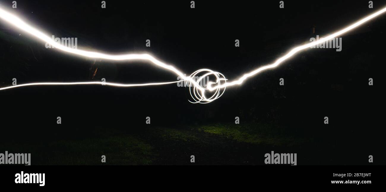 Dark abstract background with white motion paint lights on grass field ...