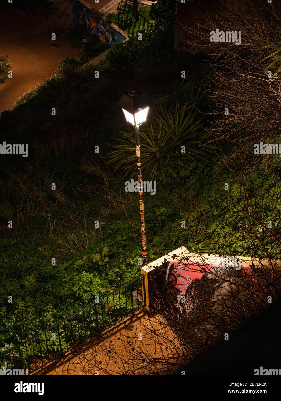 High angle shot of a lamp post on a veranda illuminating a grassy slope ...