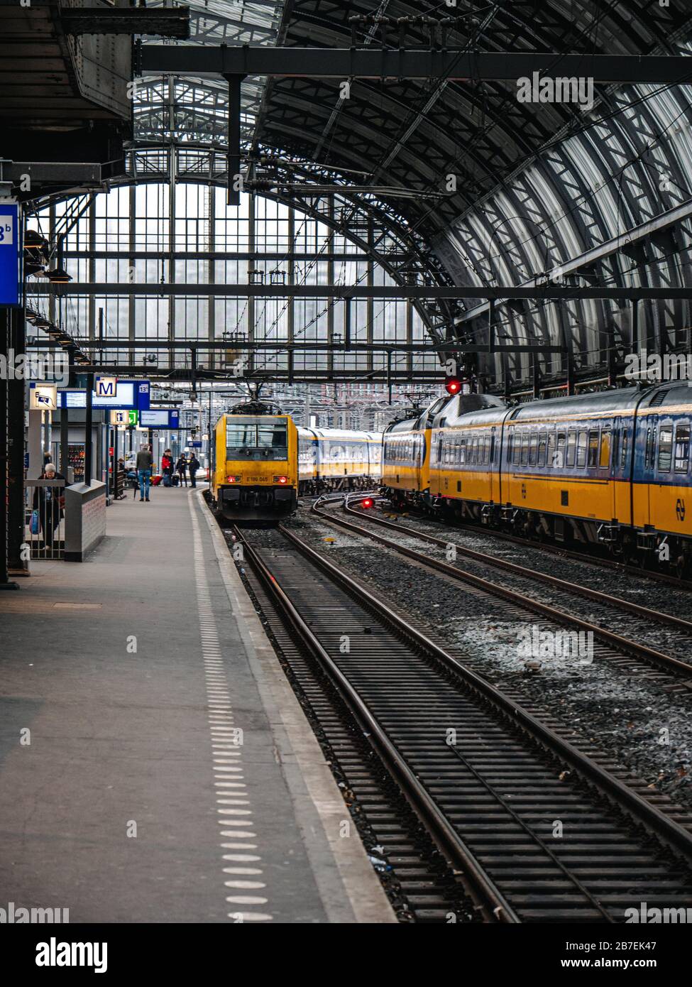 Yellow trains inside Amsterdam train station with train tracks and ...