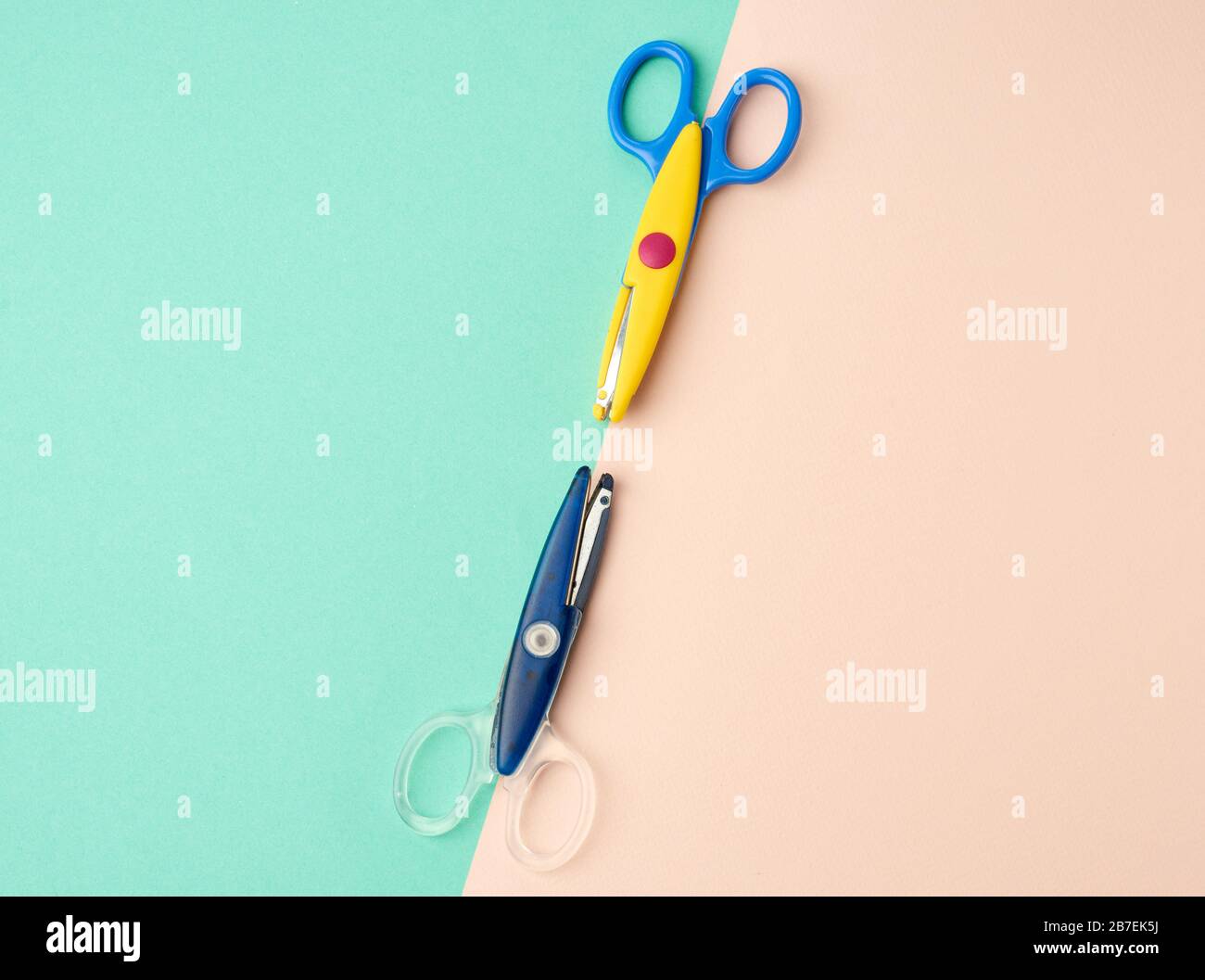 two pieces of plastic baby scissors for scrapbooking on a green ...