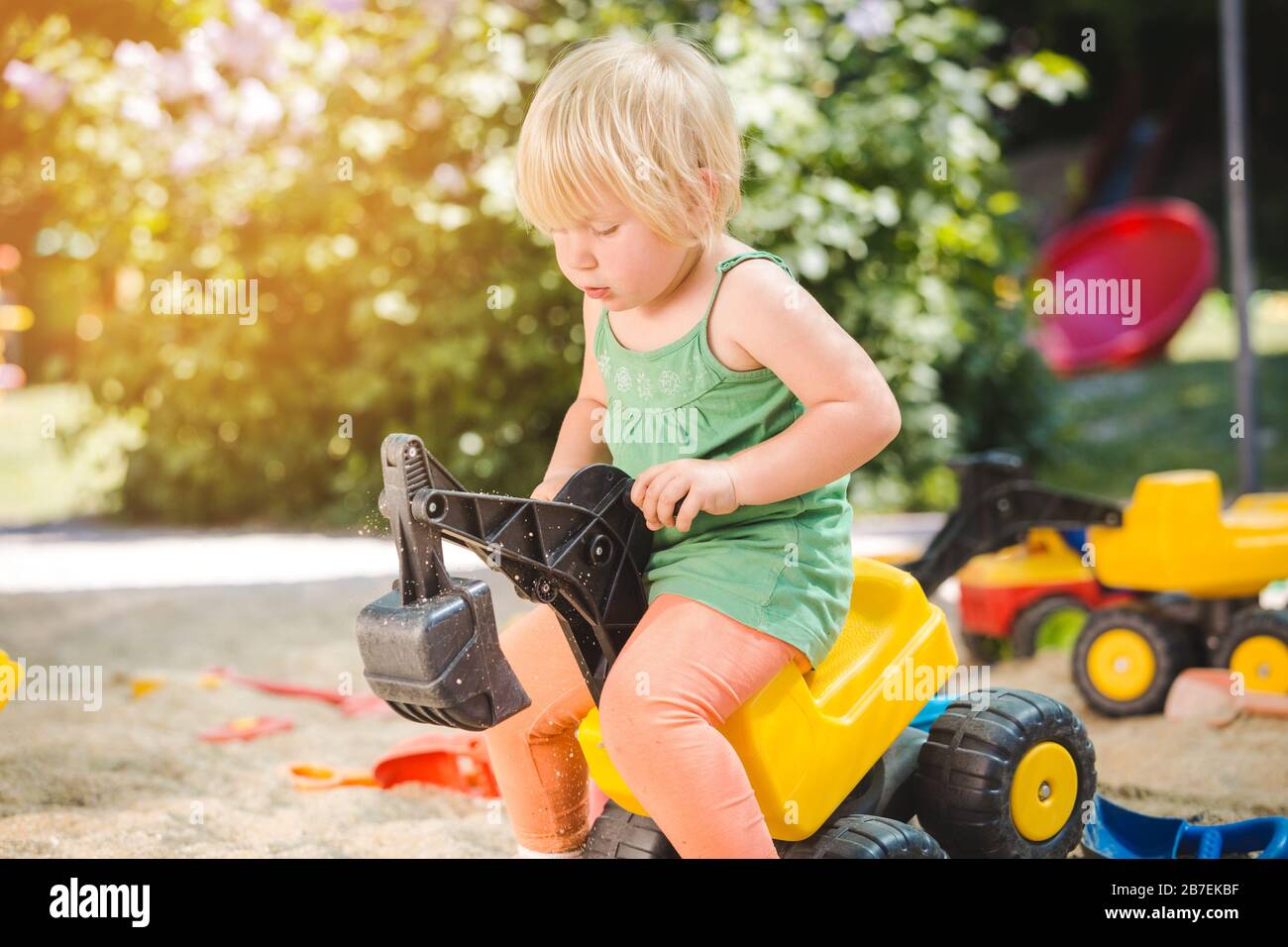 Child riding on a toy tractor on playground Stock Photo - Alamy