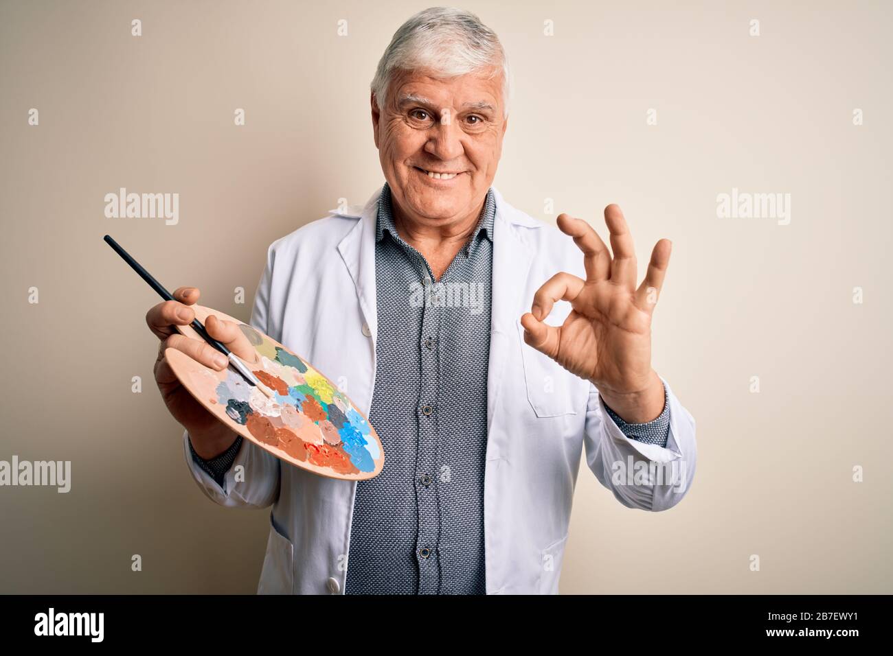 Senior handsome hoary painter man painting using brush and palette with ...