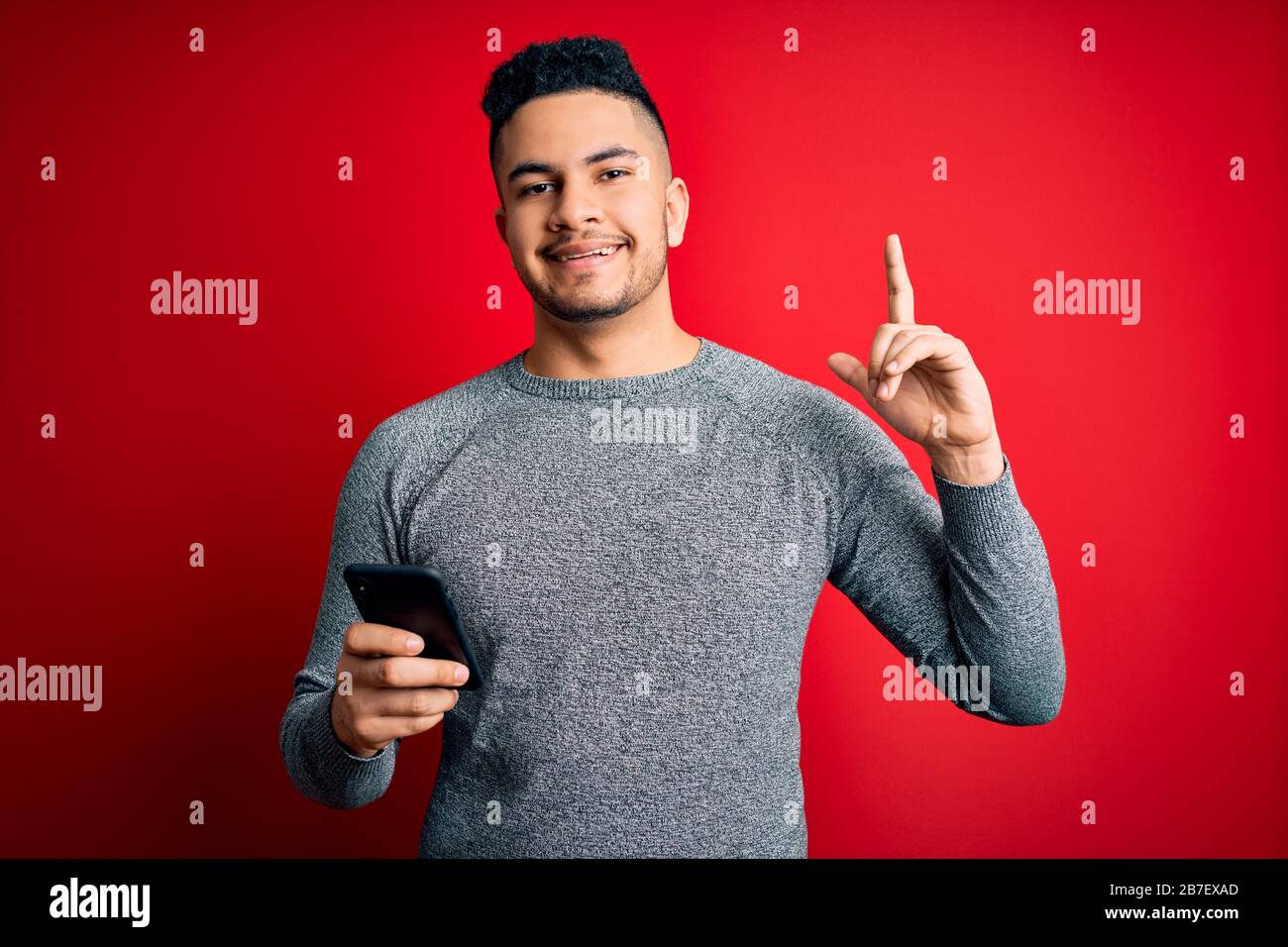 Young handsome man having conversation using smartphone over red ...