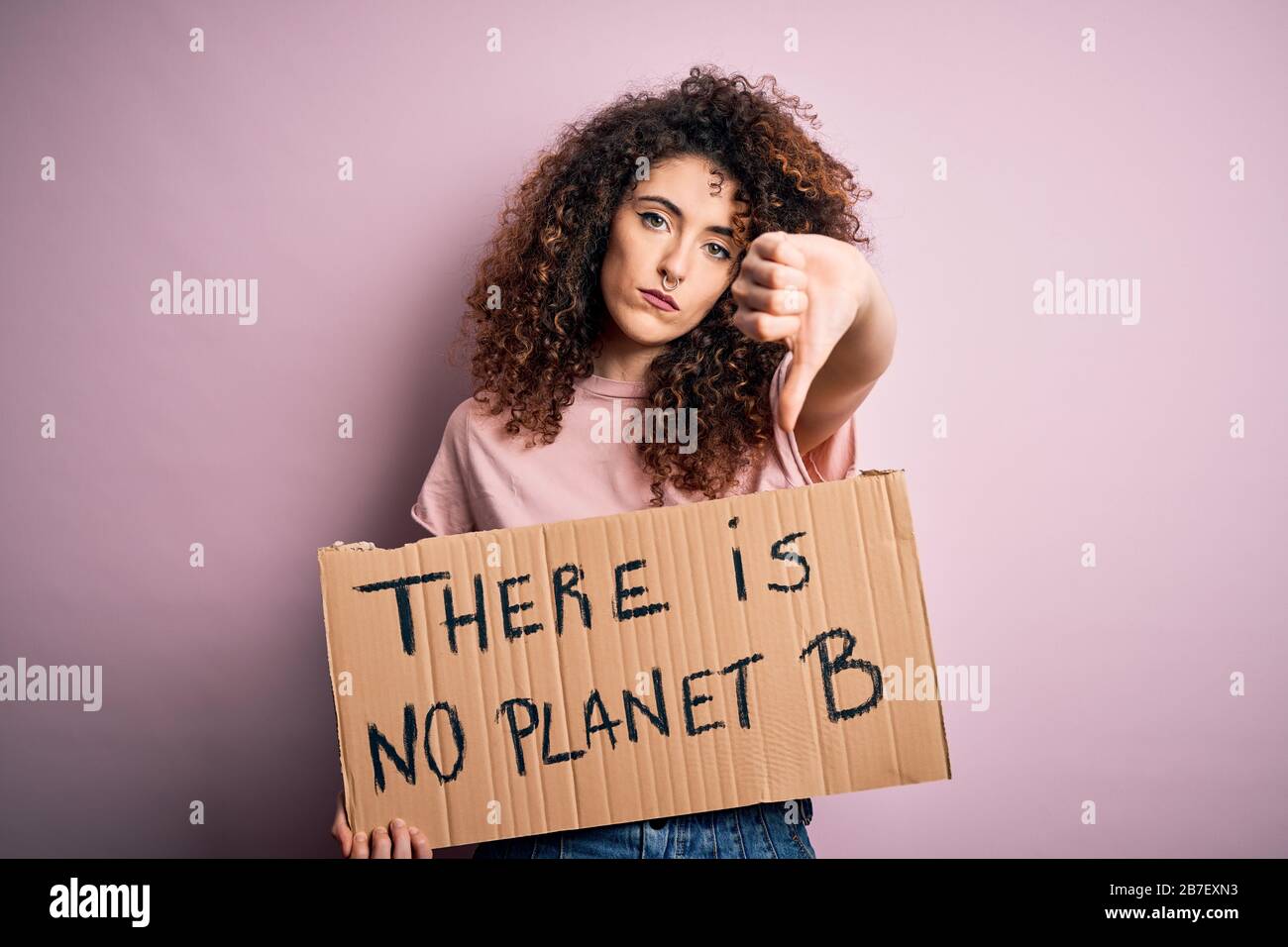 Young beautiful activist woman with curly hair and piercing protesting ...
