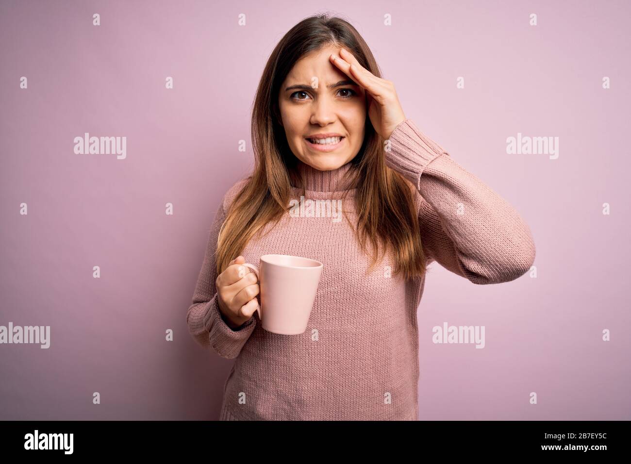 Young blonde woman drinking a cup of coffee over pink isolated ...
