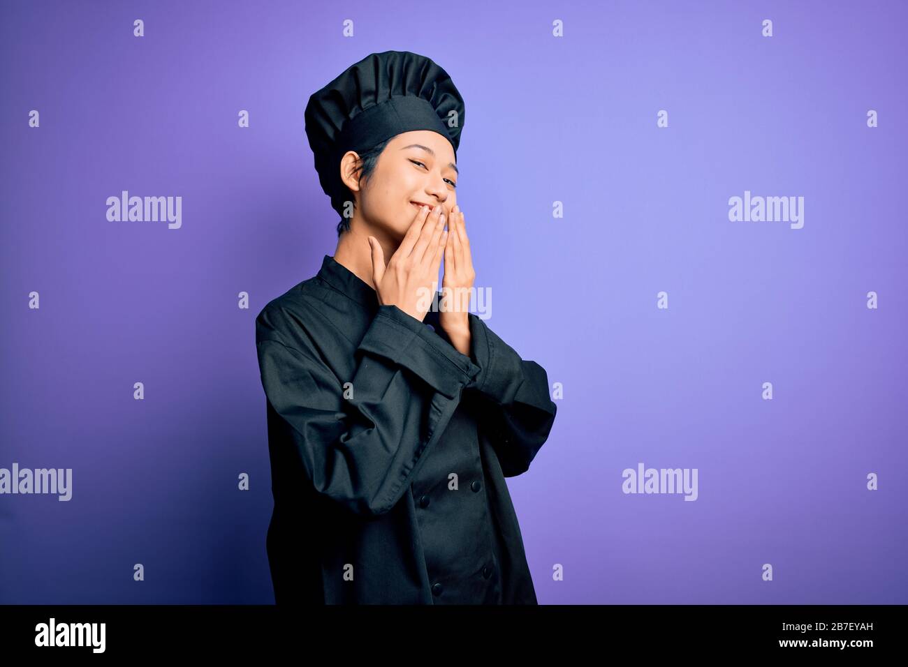 Young beautiful chinese chef woman wearing cooker uniform and hat over ...