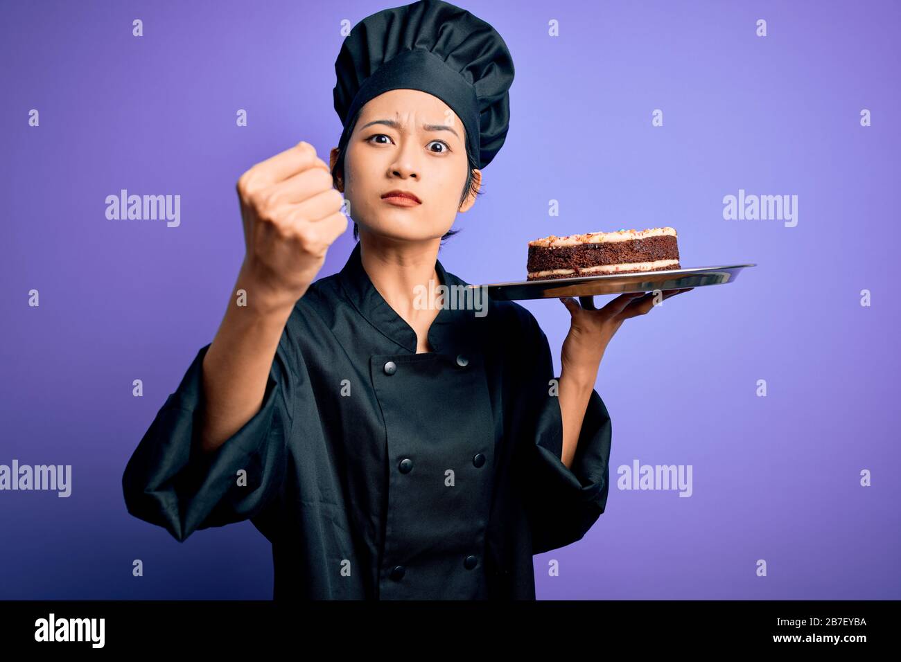 Young chinese chef woman wearing cooker uniform and hat holding tray ...