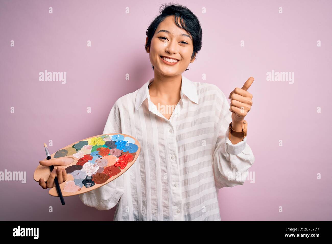 Young beautiful chinese artist woman painting using paintbrush and ...