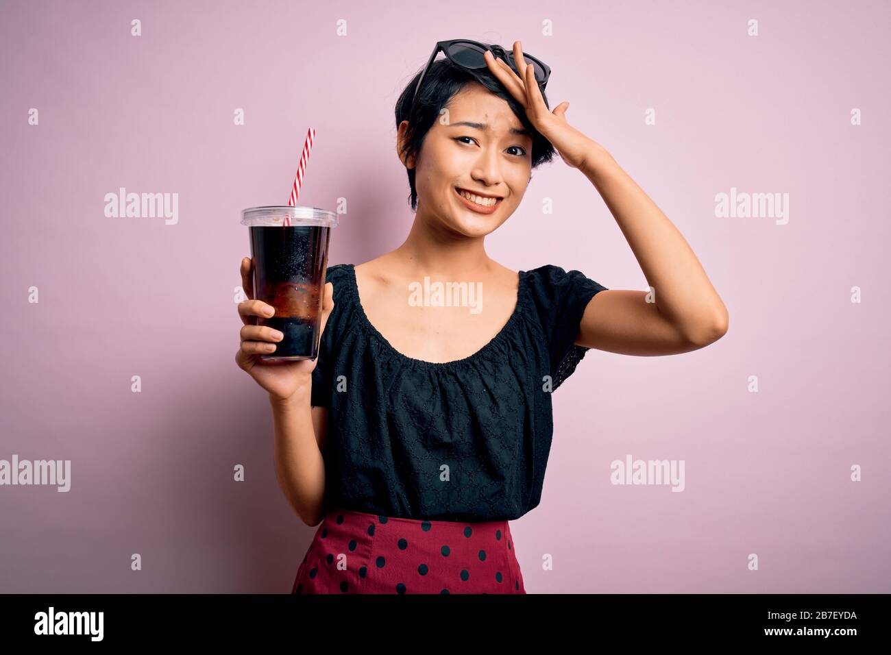 Young beautiful chinese woman drinking cola fizzy beverage using straw ...