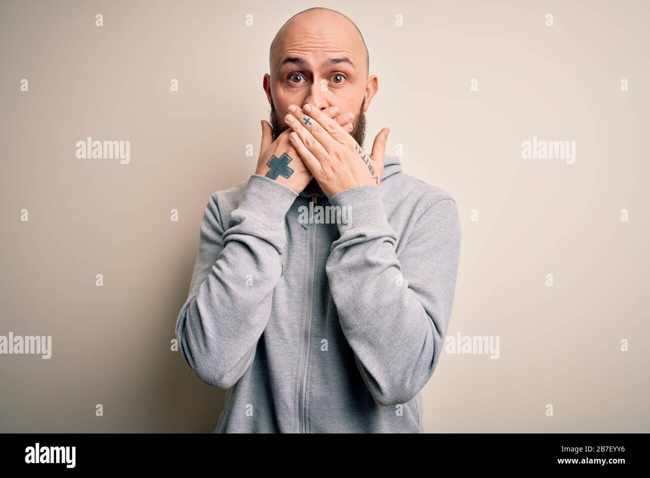 Handsome sporty bald man with beard wearing sweatshirt standing over ...