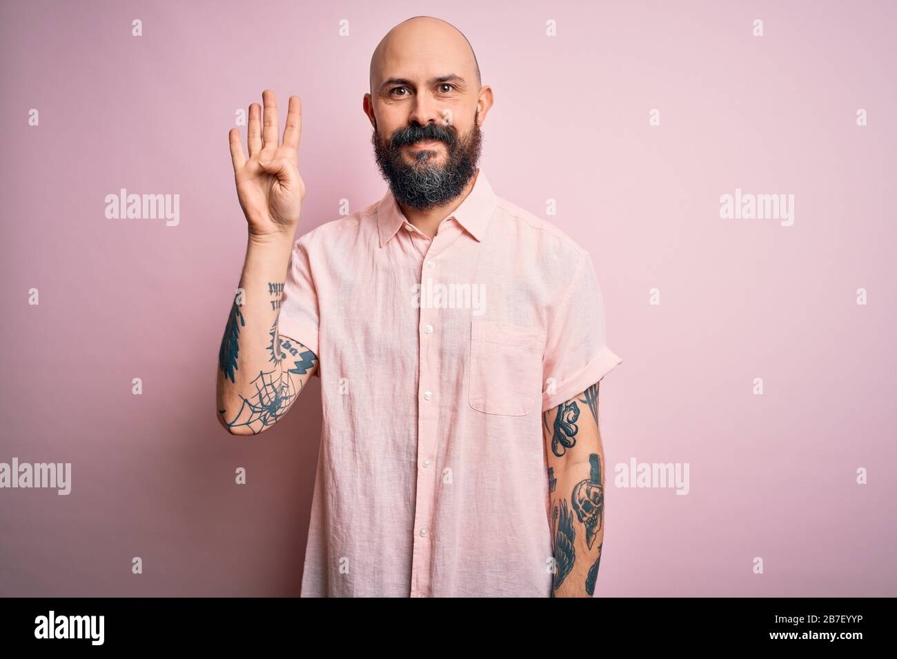 Handsome bald man with beard and tattoo wearing casual shirt over ...
