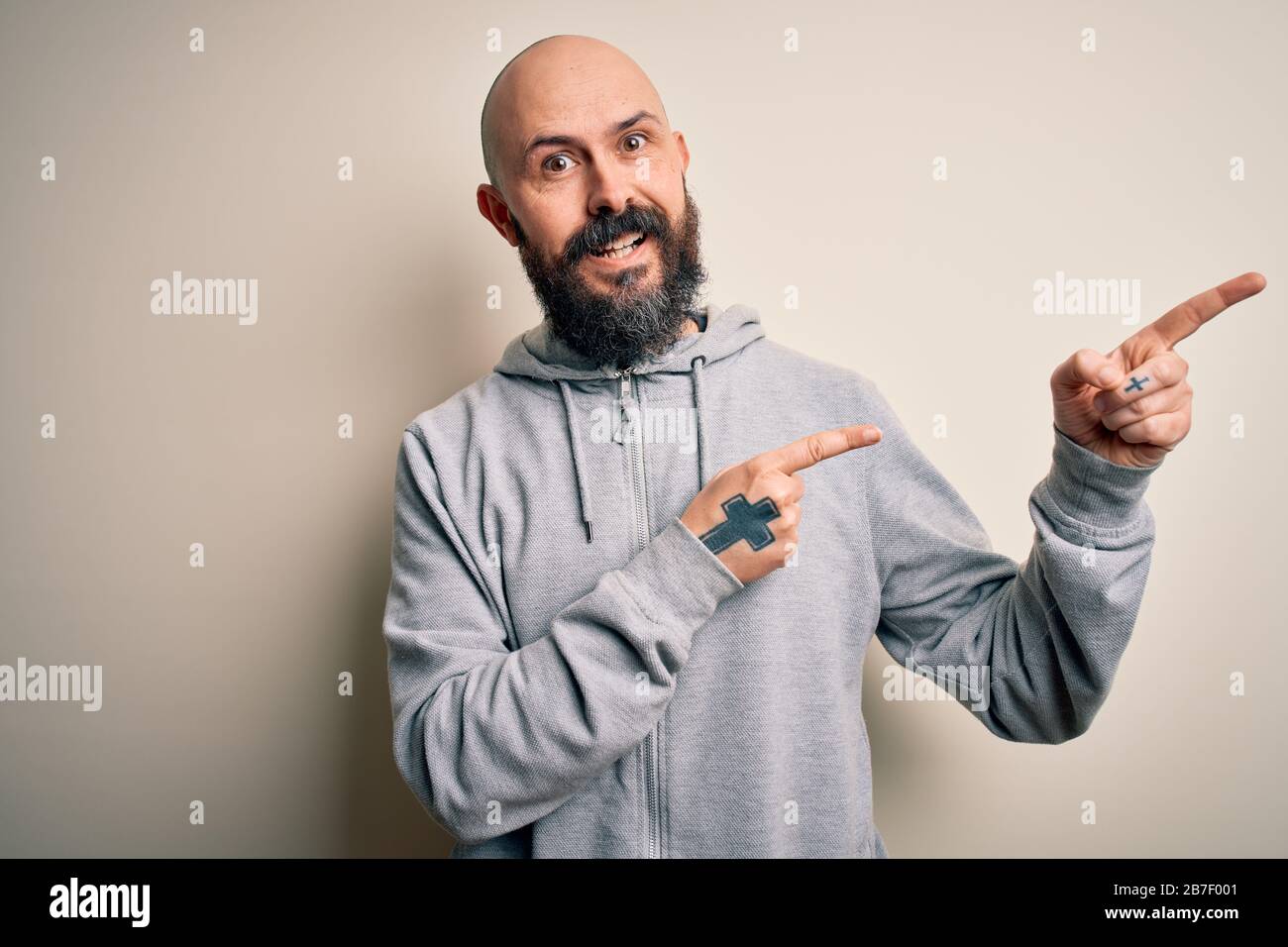 Handsome sporty bald man with beard wearing sweatshirt standing over ...