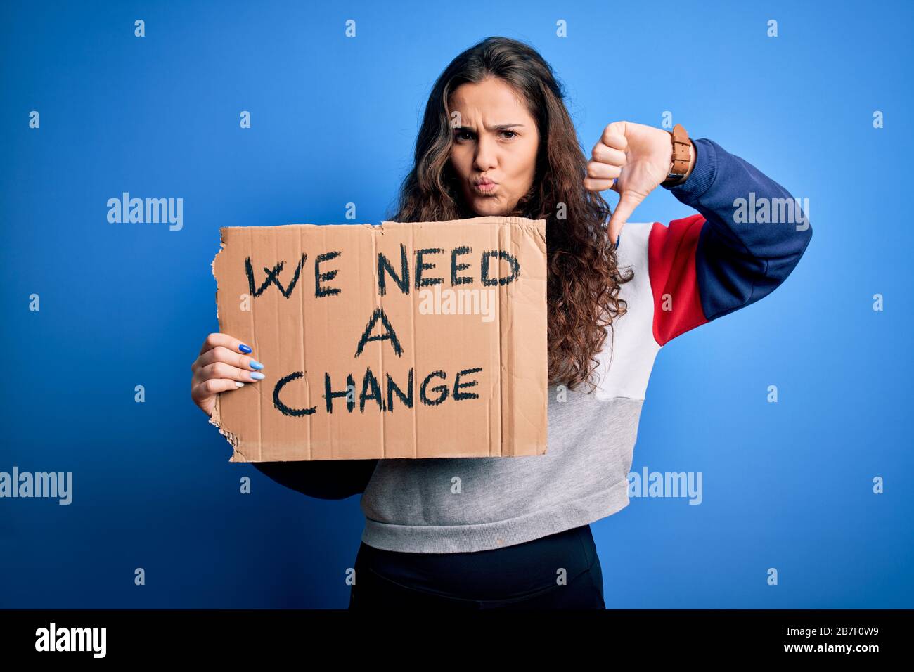Young beautiful activist woman holding banner with change message over ...