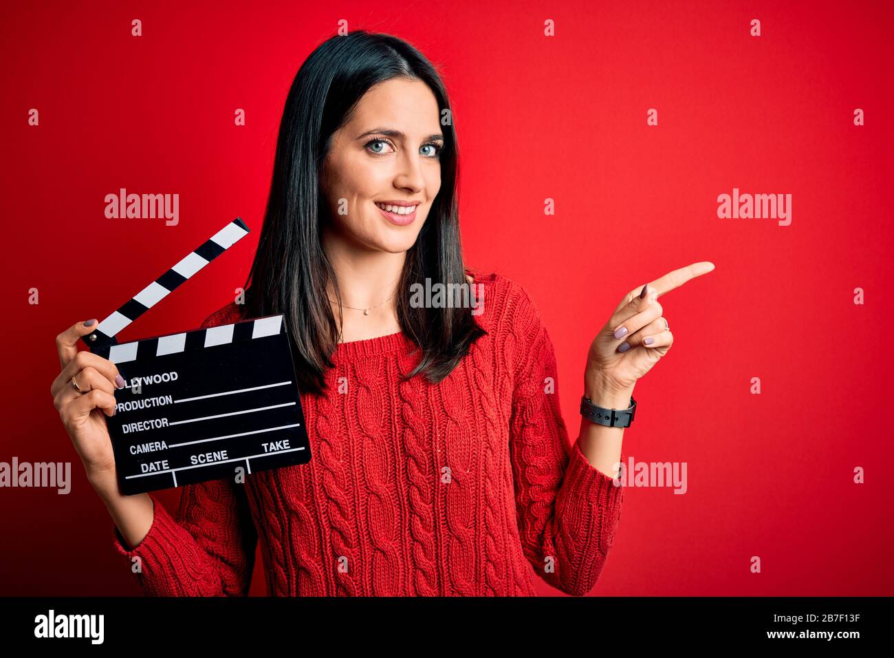 Young director woman with blue eyes making movie holding clapboard over ...