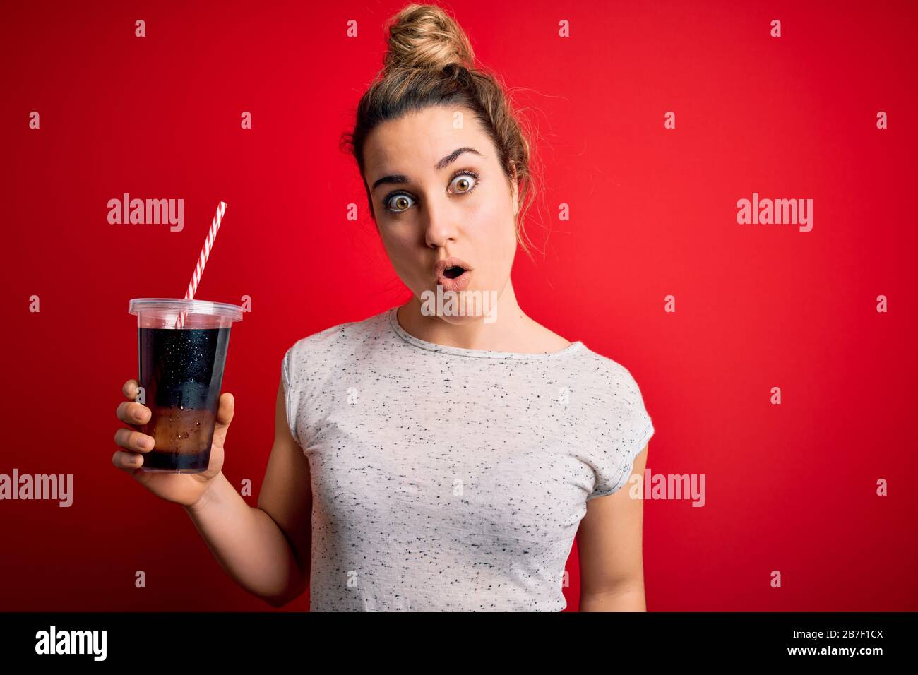 Beautiful blonde woman drinking cola fizzy beverage to refreshment over ...