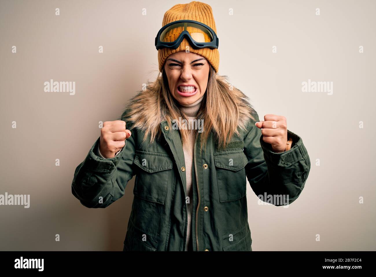 Young brunette skier woman wearing snow clothes and ski goggles over ...