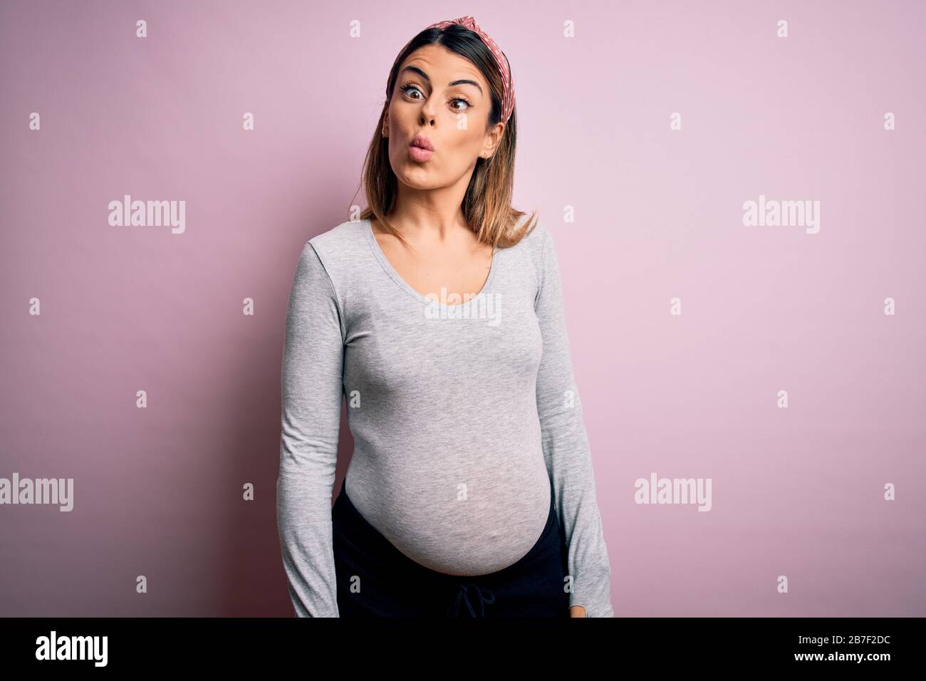 Young beautiful brunette woman pregnant expecting baby over isolated ...