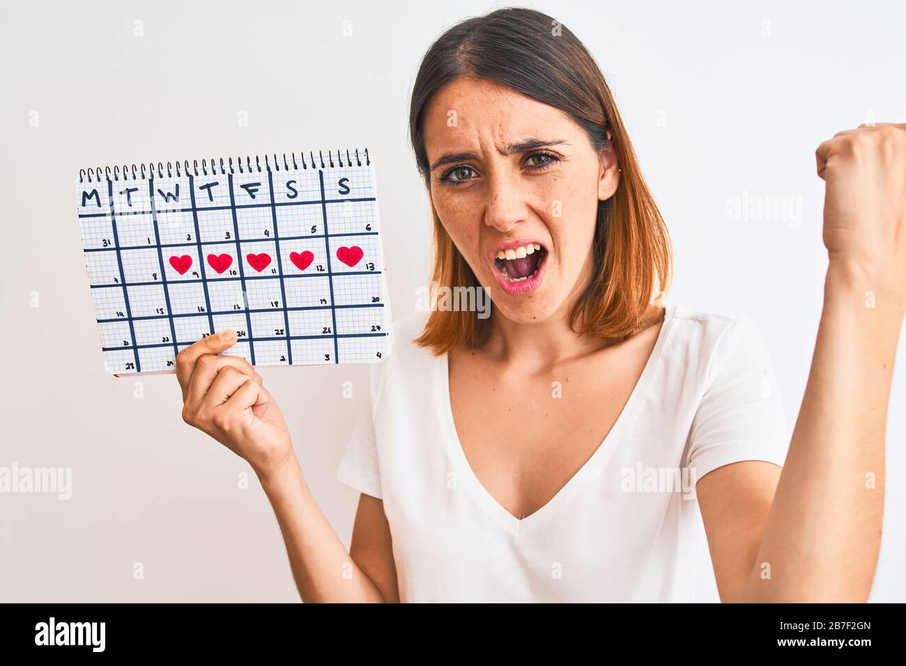 Beautiful redhead woman holding menstruation calendar over isolated ...