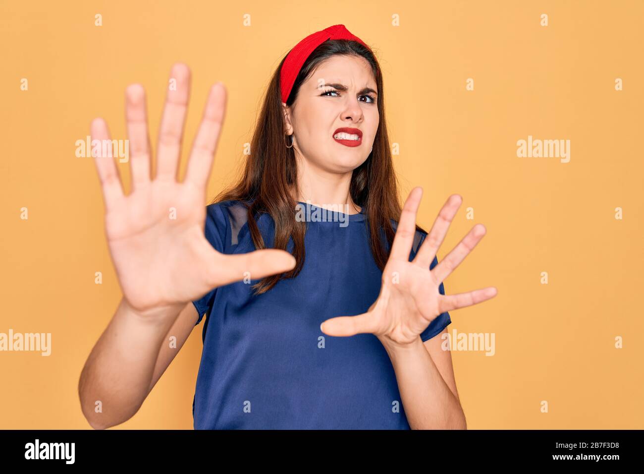 Young beautiful brunette woman wearing red lips over yellow background ...