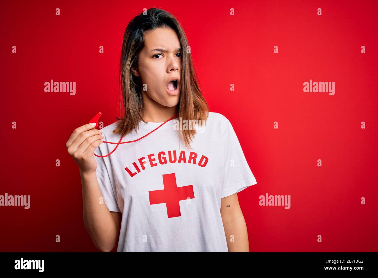Young beautiful brunette lifeguard girl wearing t-shirt with red cross ...