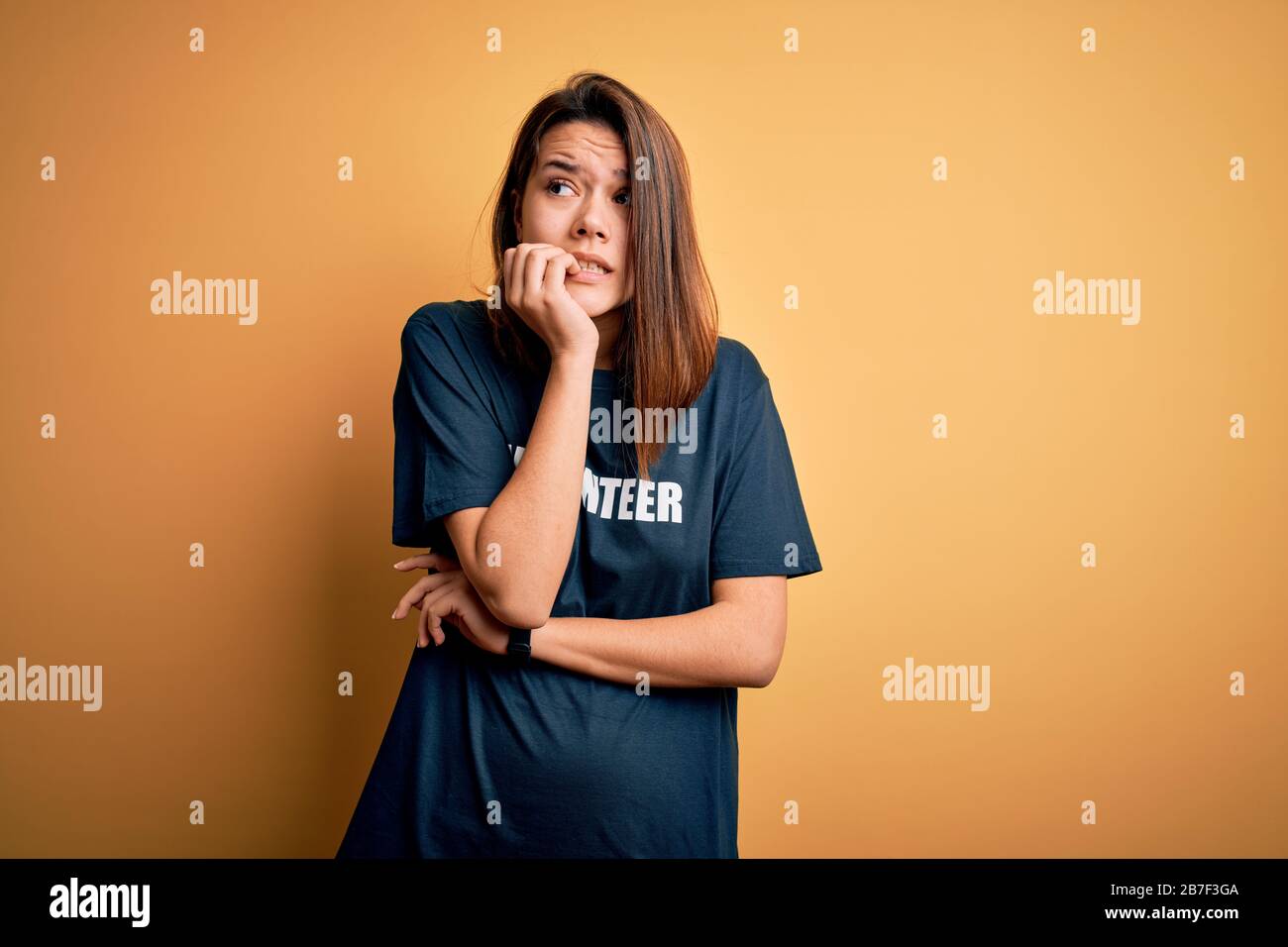Young beautiful brunette girl doing volunteering wearing t-shirt with ...