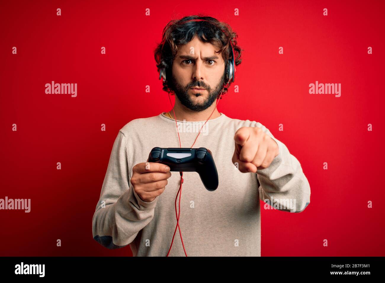Young gamer man with curly hair and beard playing video game using ...