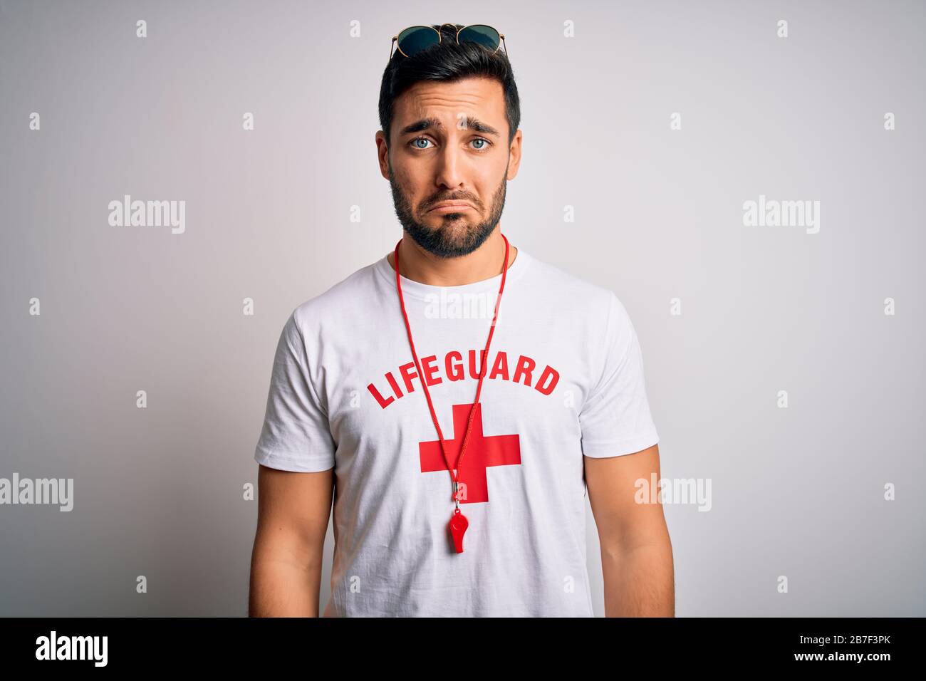 Young handsome lifeguard man with beard wearing t-shirt with red cross ...