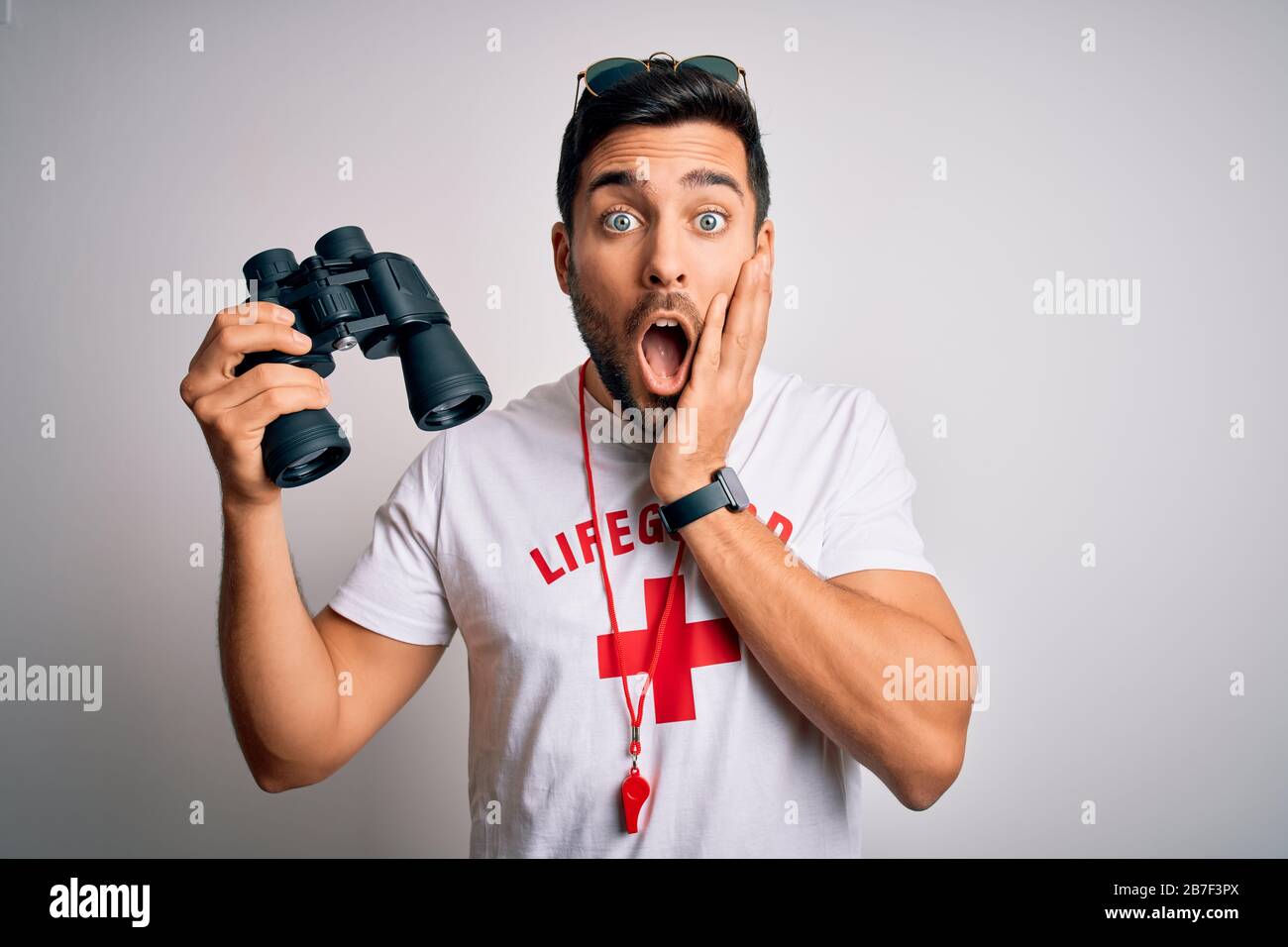 Young lifeguard man with beard wearing t-shirt with red cross and ...