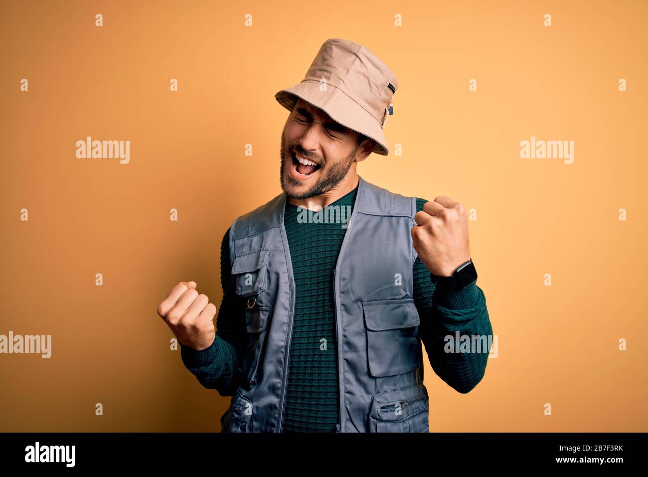 Handsome tourist man with beard on vacation wearing explorer hat over ...