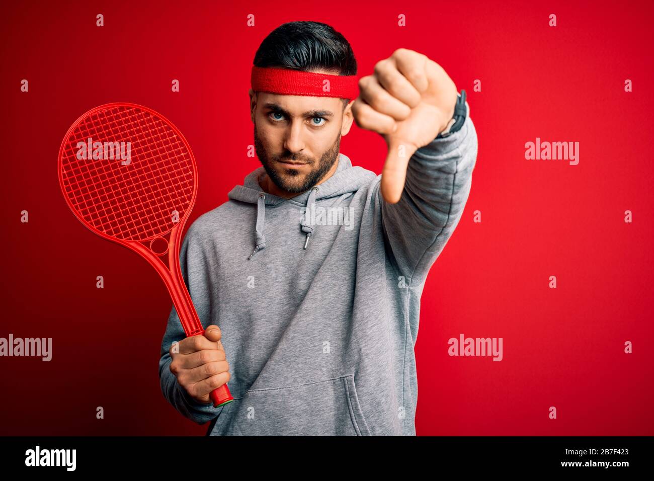 Young handsome sportsman holding tennis racket wearing sportswear over ...