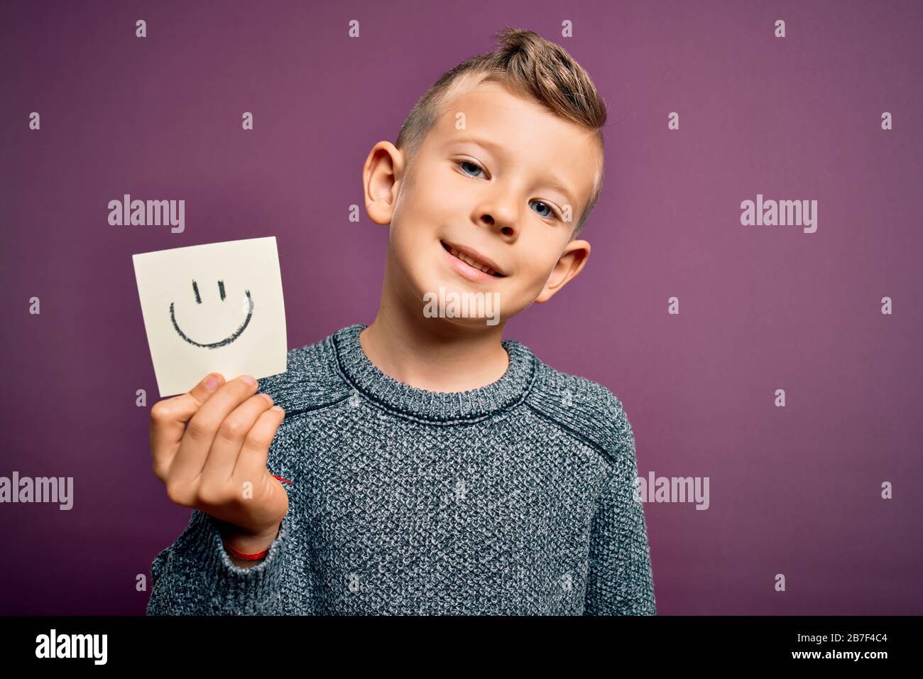 Young little caucasian kid showing smiley face on a paper note as happy ...