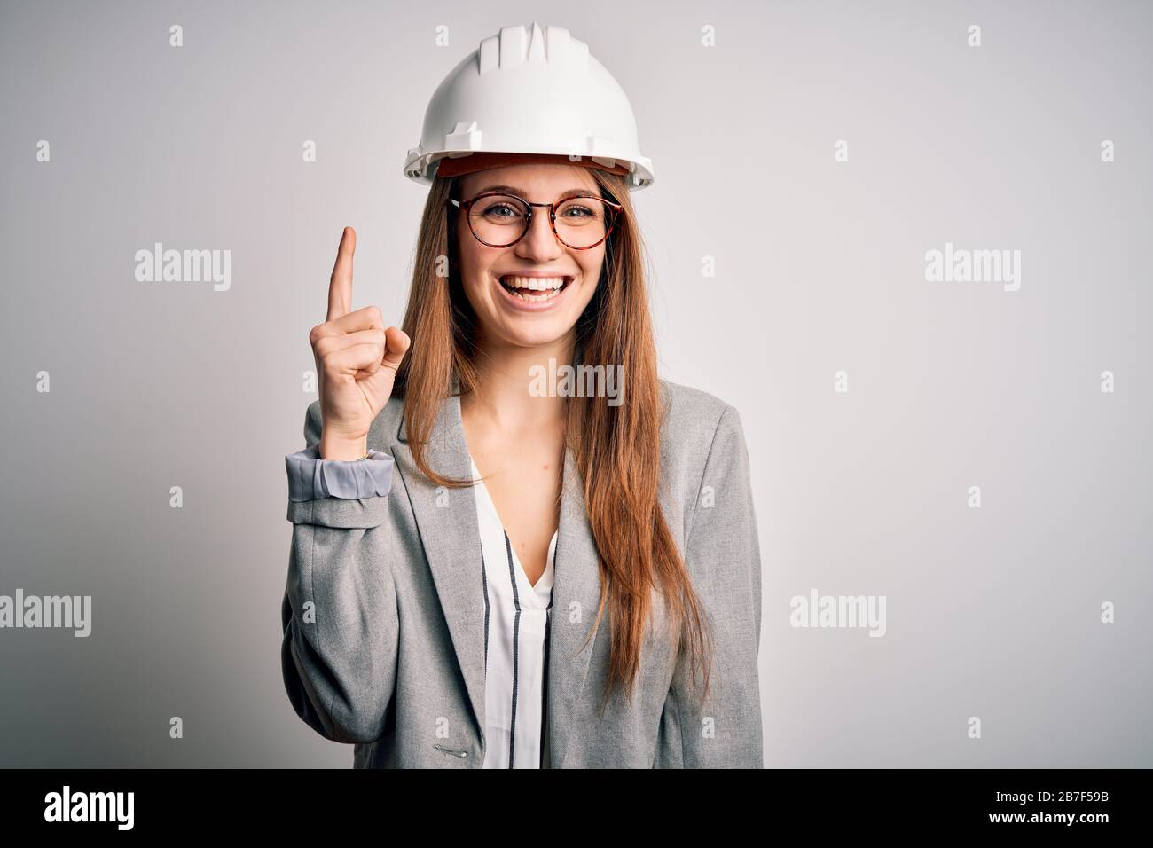 Young beautiful redhead architect woman wearing security helmet over ... Young beautiful redhead architect woman wearing security helmet over ...