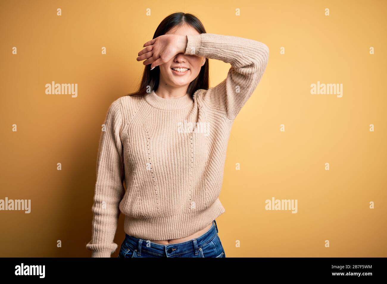 Young beautiful asian woman wearing casual sweater over yellow isolated ...