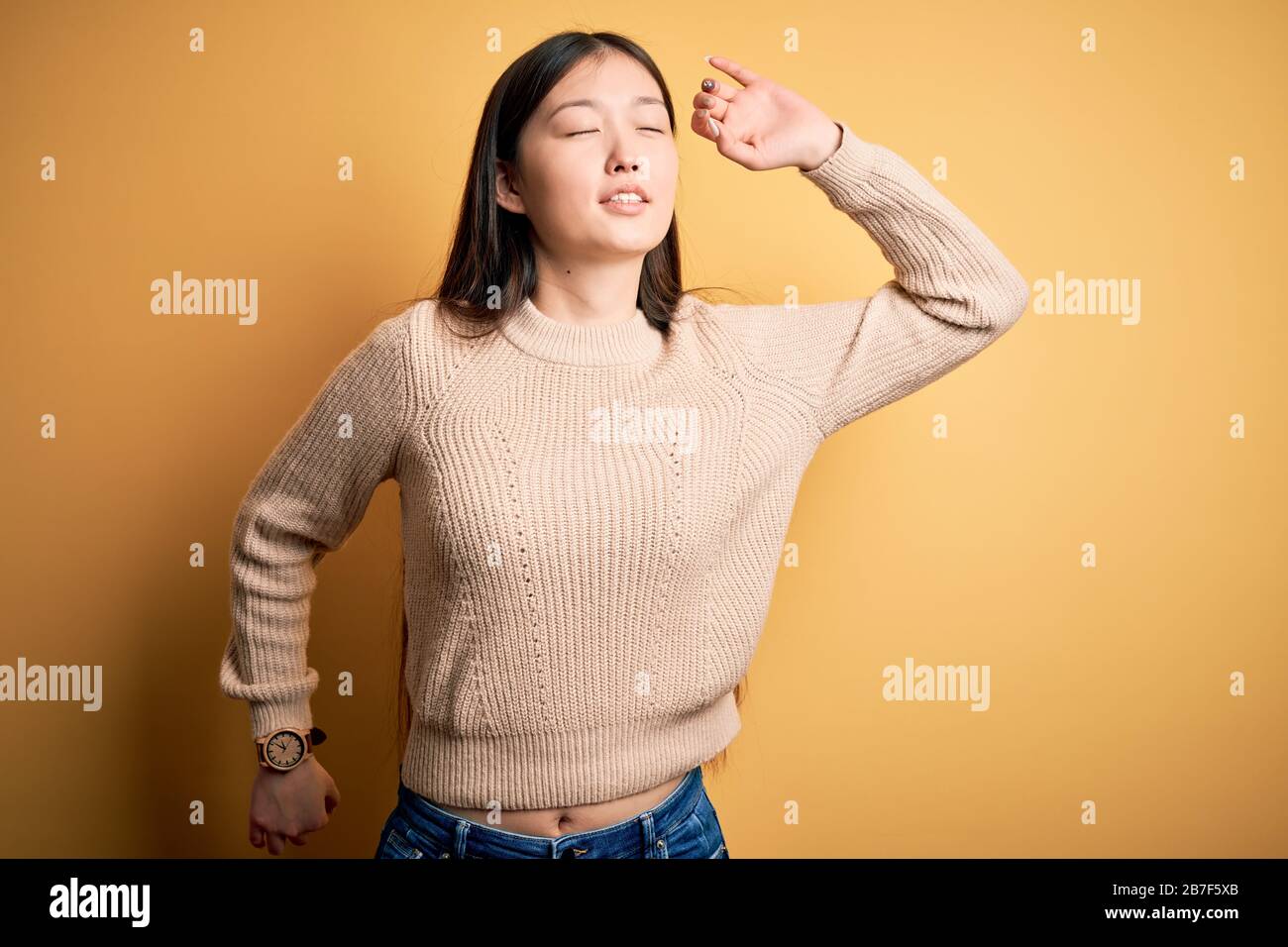 Young beautiful asian woman wearing casual sweater over yellow isolated ...