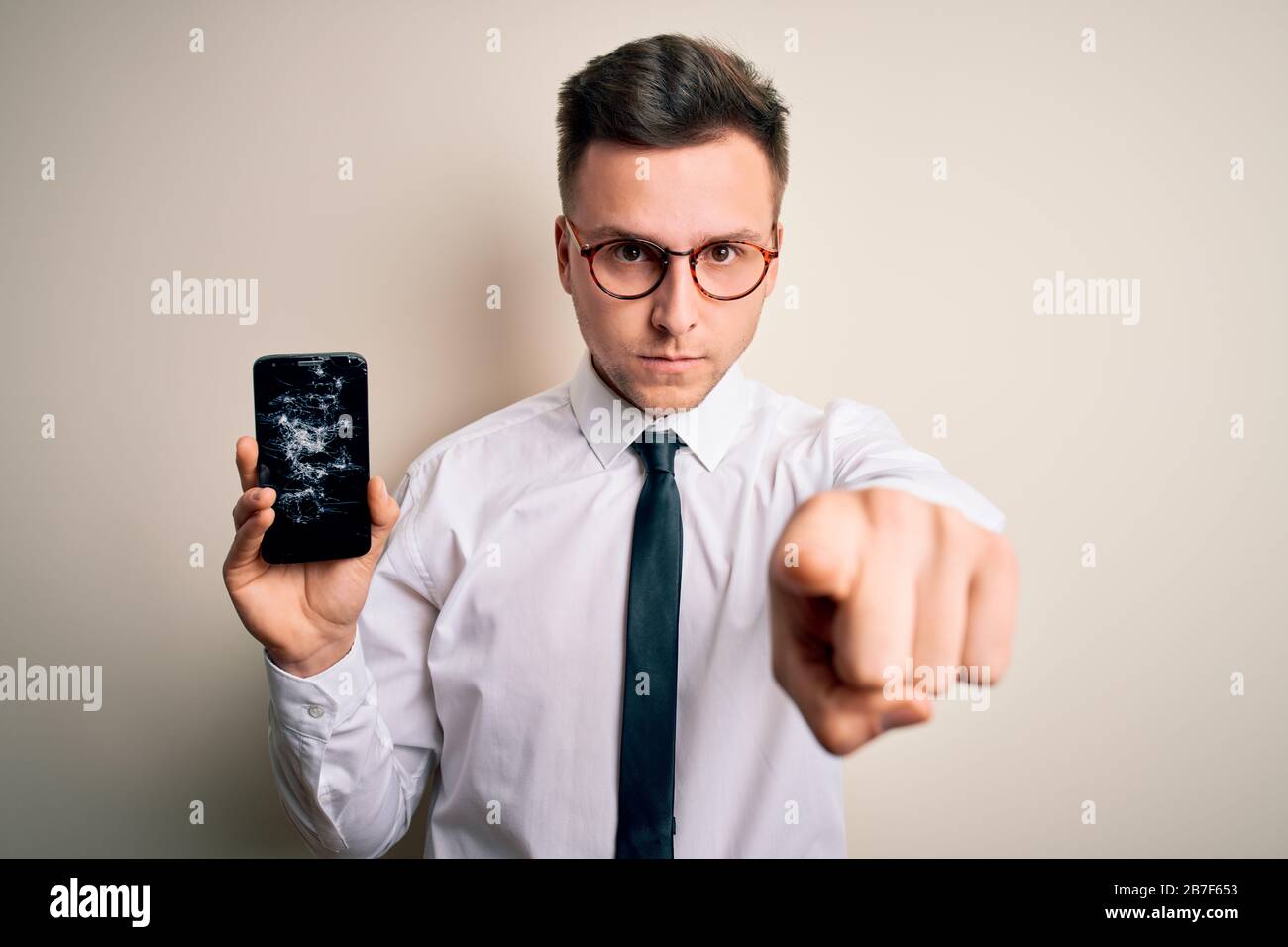 Young handsome caucasian man holding smartphone with broken screen over ...