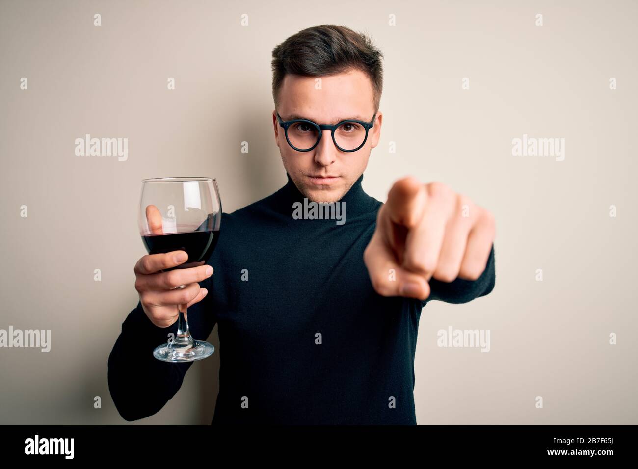 Young handsome caucasian man drinking an alcoholic glass of red wine ...
